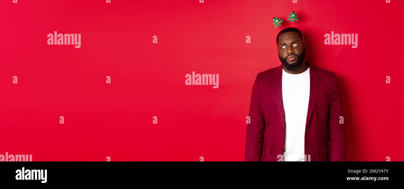 Merry Christmas. Annoyed african american man roll eyes, wearing silly ...