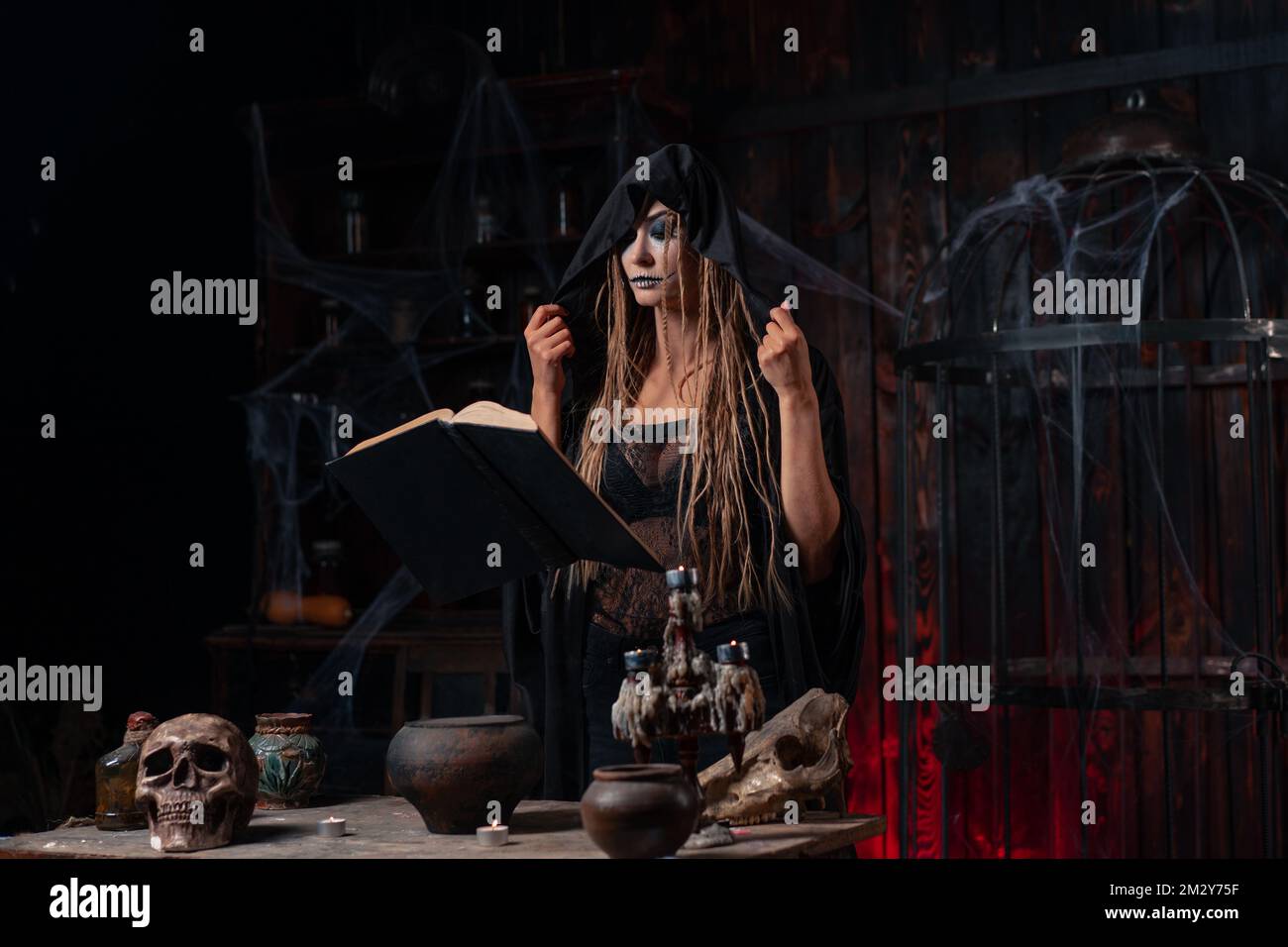 Witch dressed black hood with dreadlocks standing dark dungeon room use ...