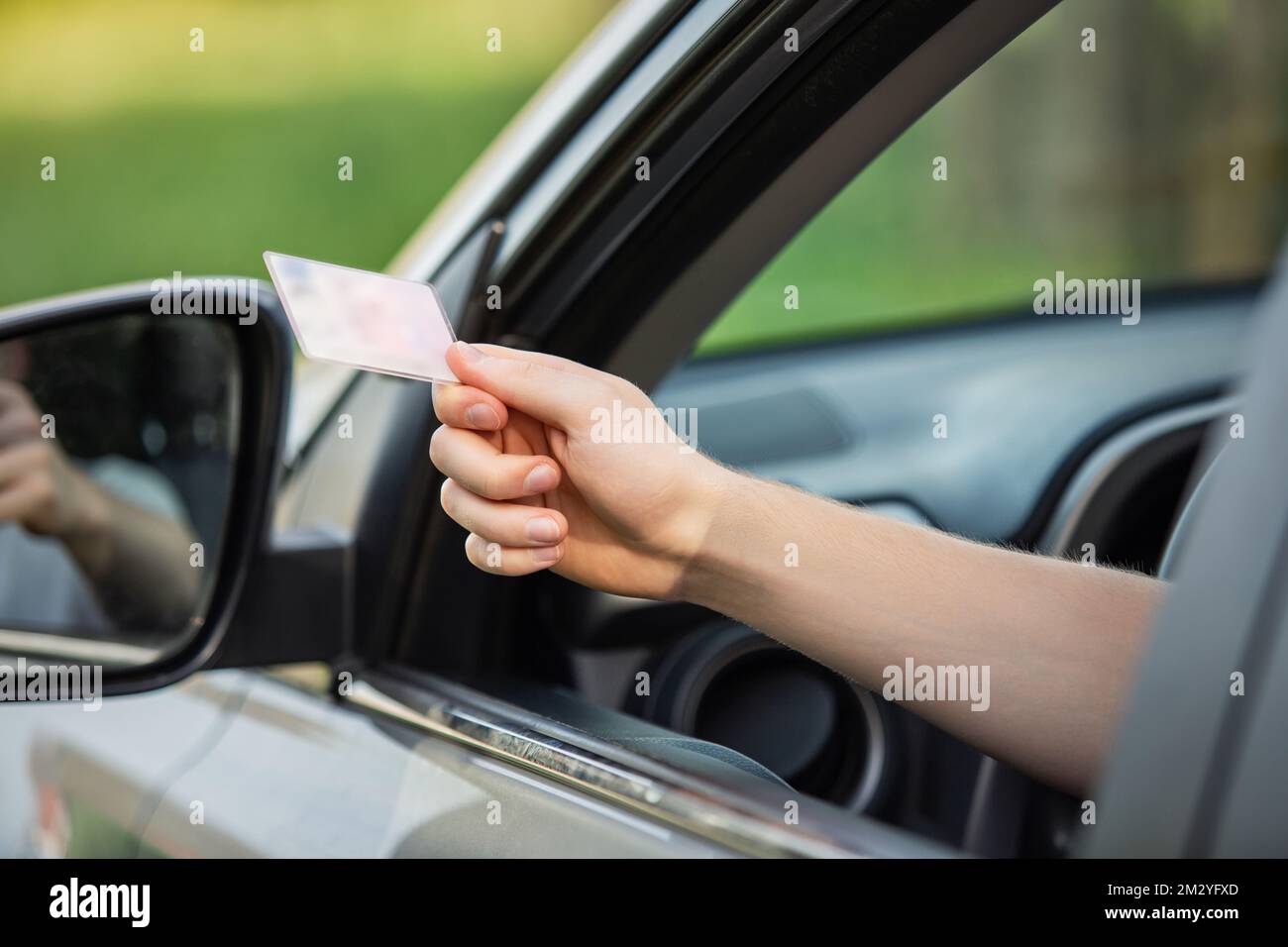 Close up person hand out of the car window holding the driver license ...