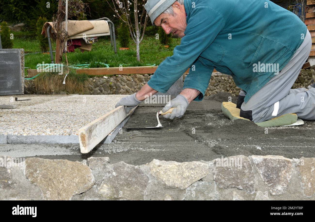 The bricklayer levels the floor using a spirit level and sand before ...