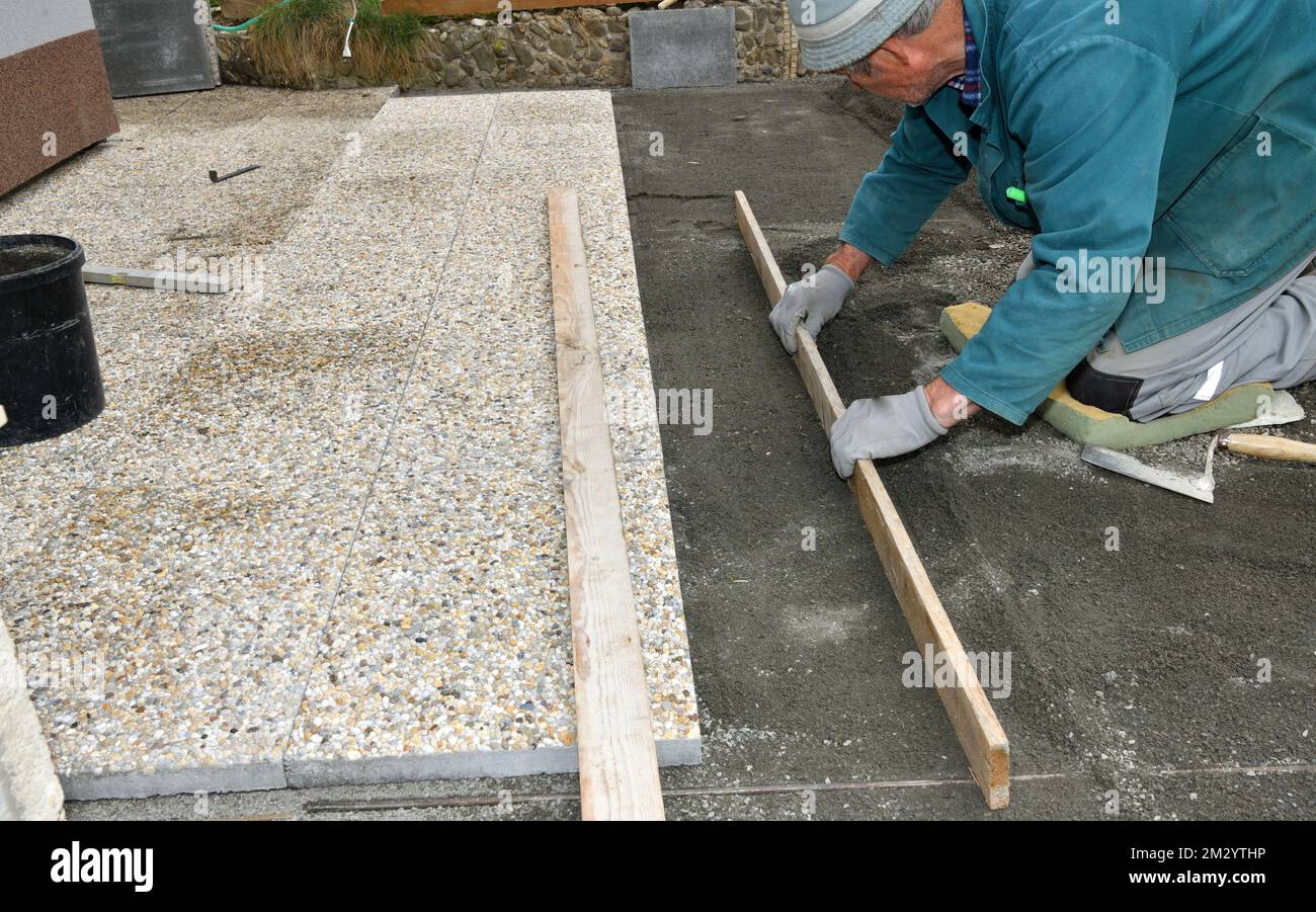 The bricklayer levels the floor using a spirit level and sand before ...