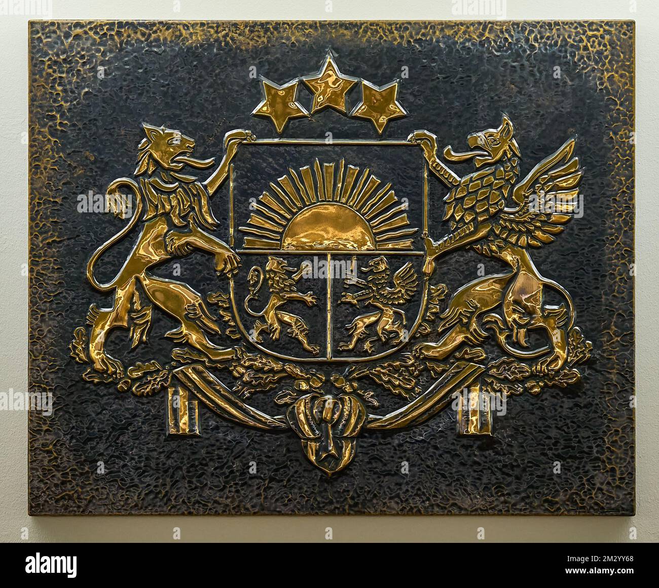 Closeup of gold color coat of arms of Latvia embossed on a relief dark ...