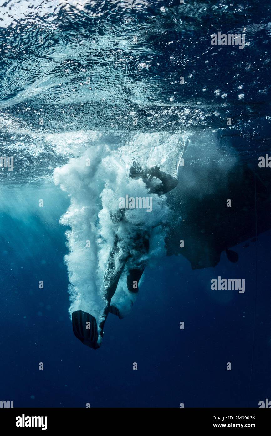 A scuba diver jumping from a boat into the sea while creating a lot of ...