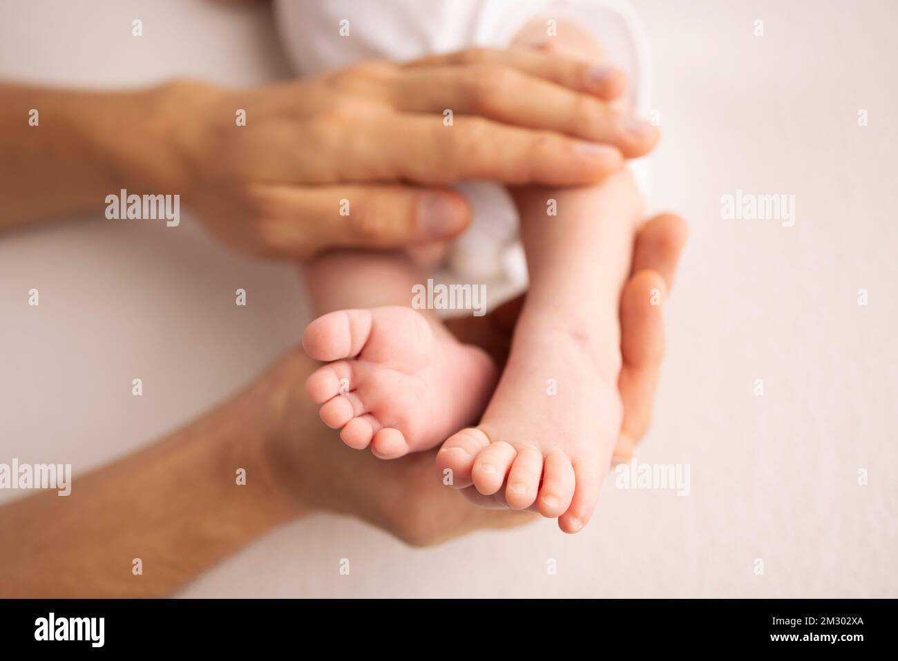 Children's foot in the hands of mother, father, parents. Feet of a tiny ...