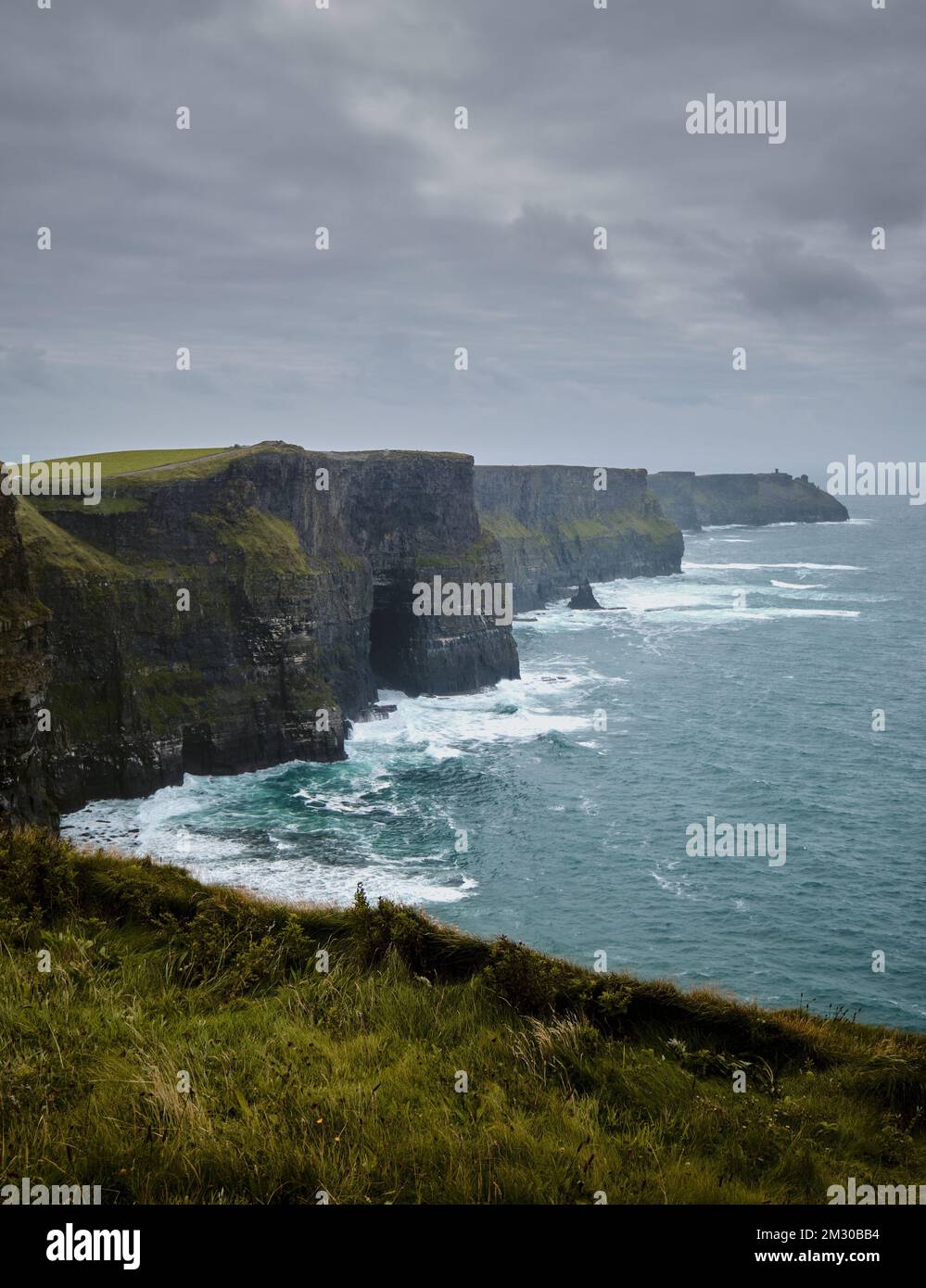 A scenic vertical view of the evergreen Cliffs of Moher in Ireland on a ...