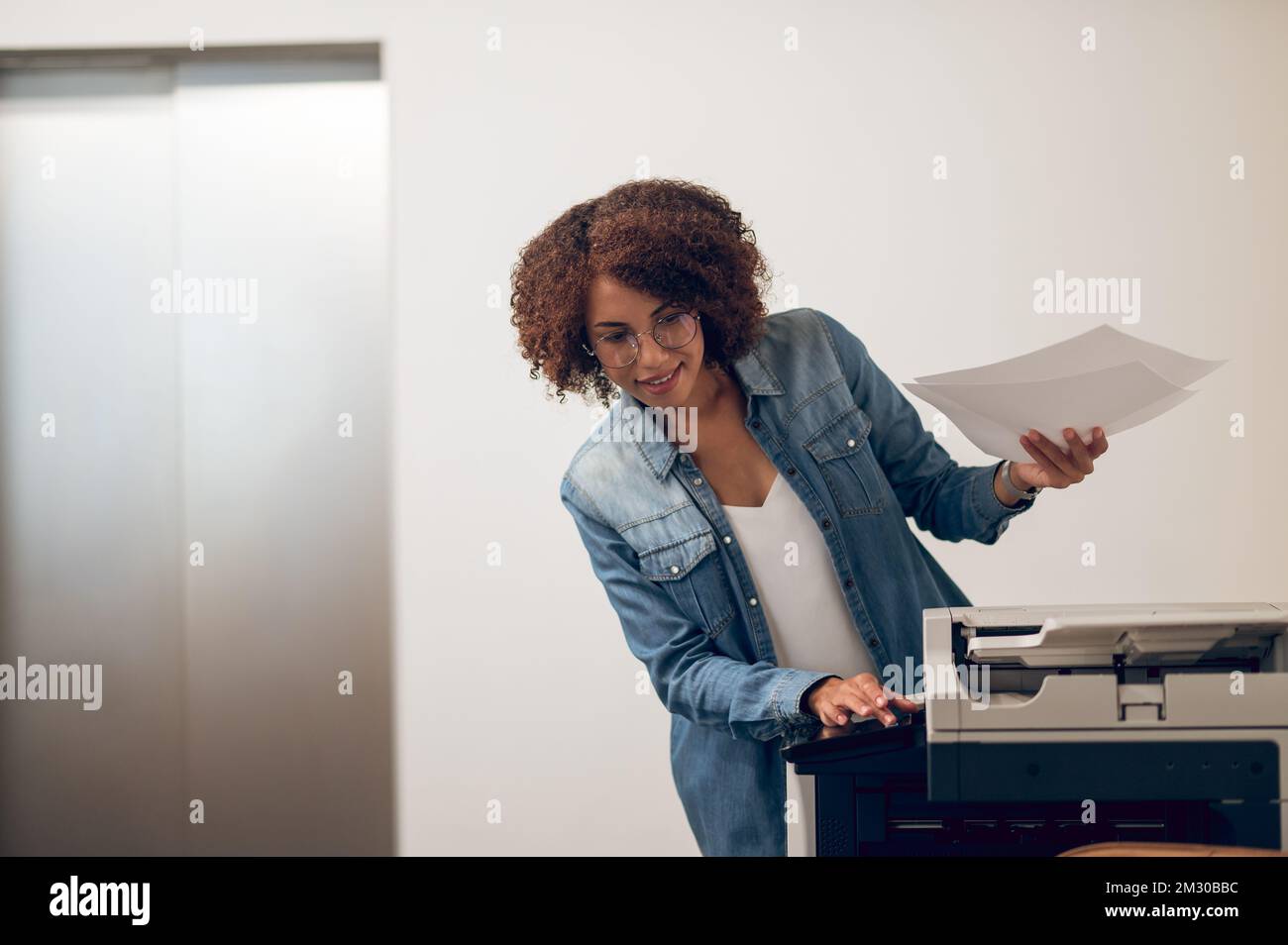 Joyous focused female secretary using the copy machine Stock Photo - Alamy