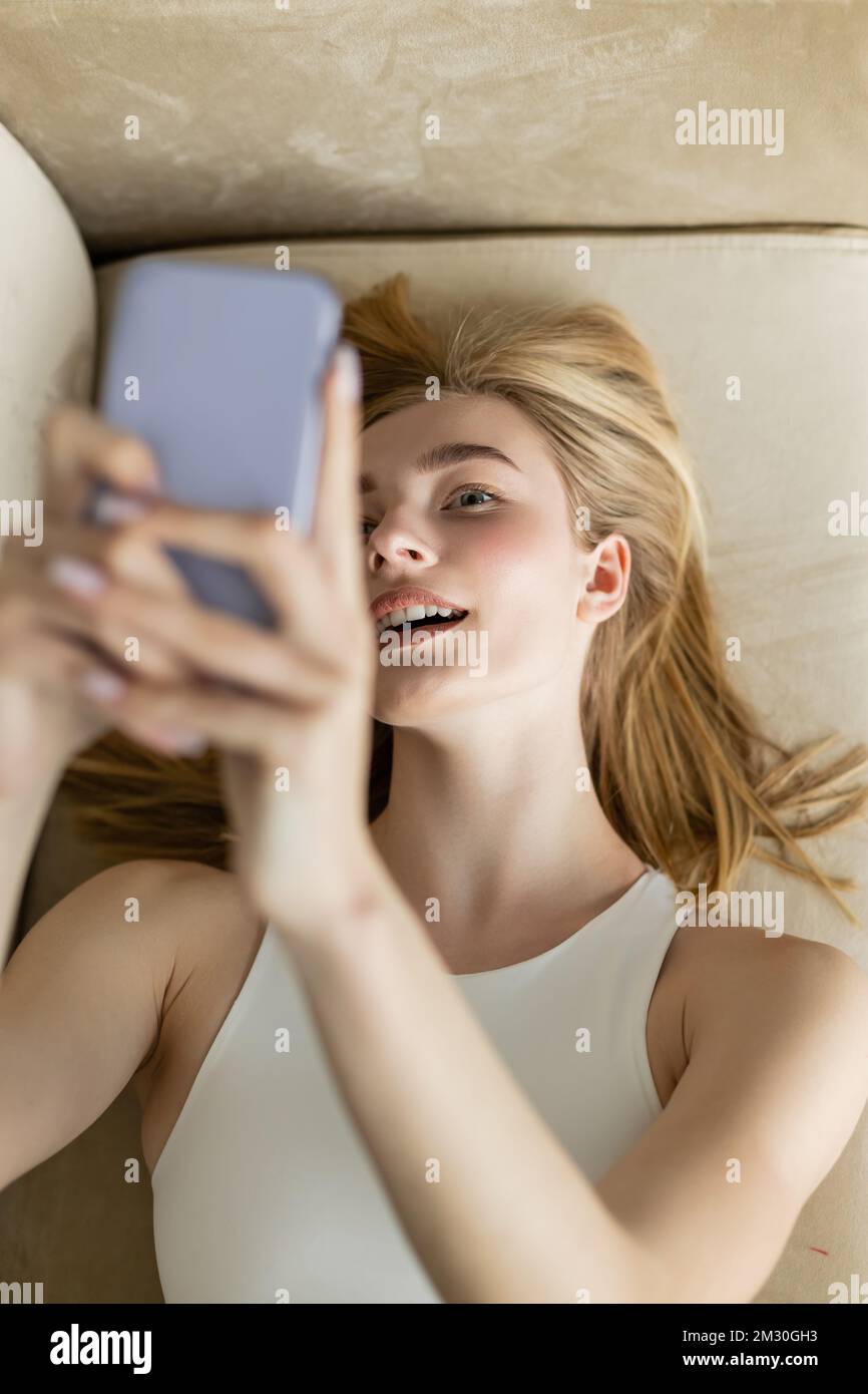 Top view of young woman with opened mouth taking selfie on smartphone on couch,stock image Stock ...