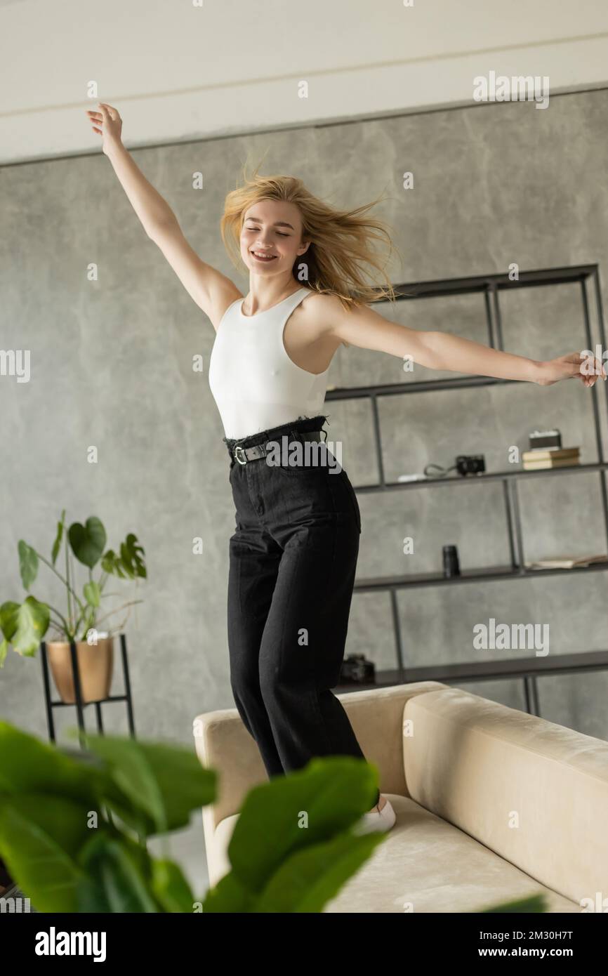 Excited woman dancing on sofa hi-res stock photography and images - Alamy