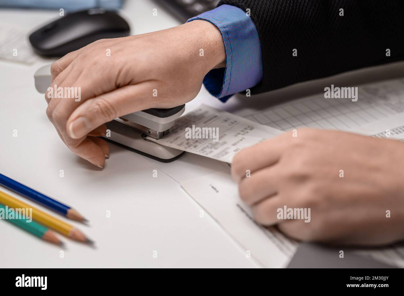 Woman accountant staples checks with a stapler at the office on the ...