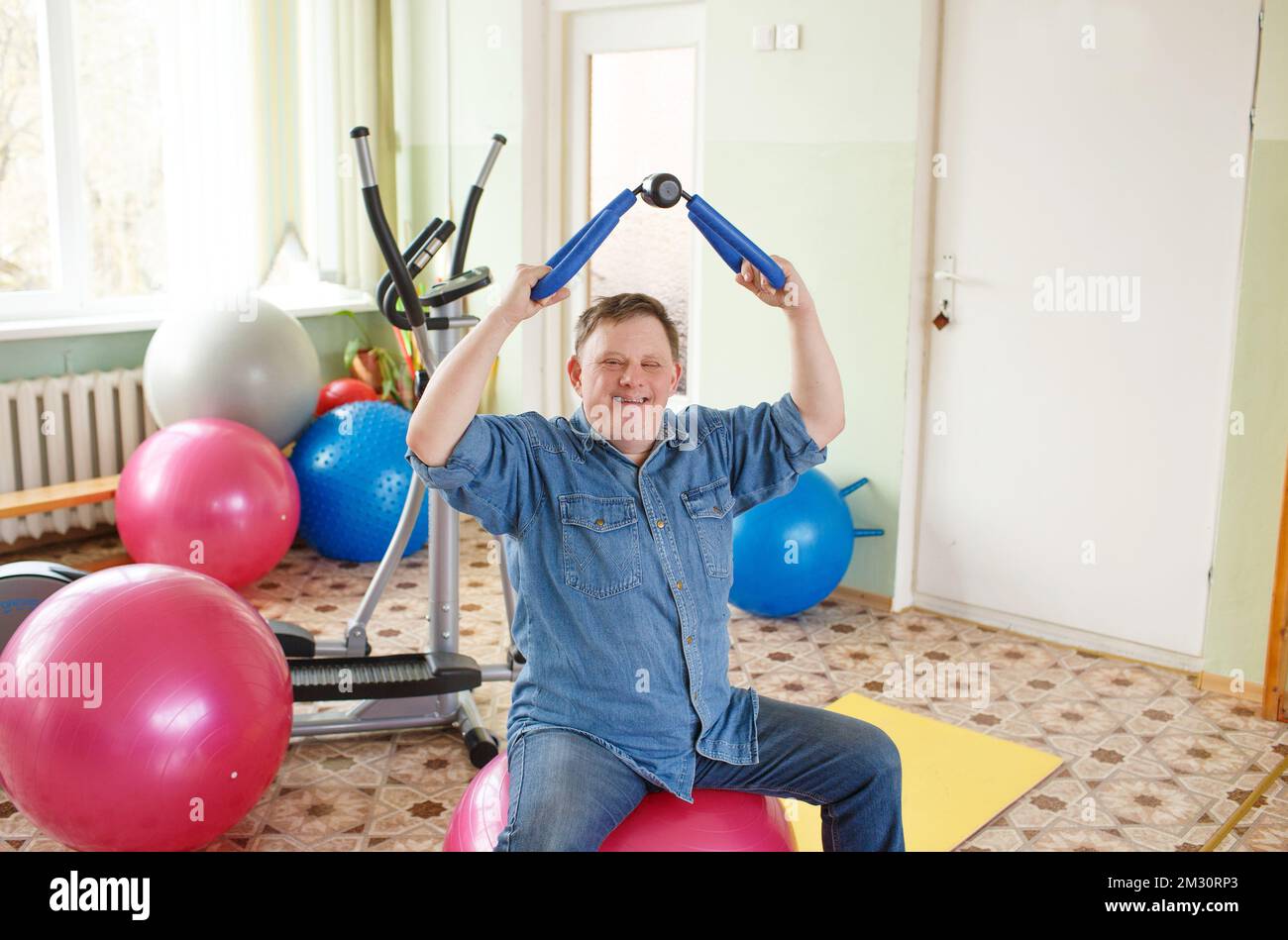 a man with down syndrome sits on a large inflatable ball with a ...