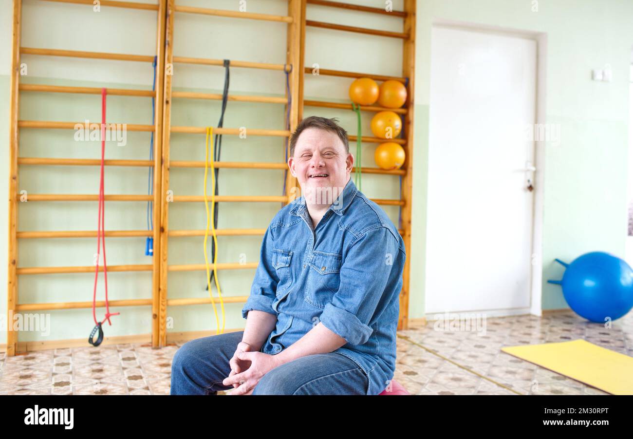 a man with down syndrome sits on a large inflatable ball in a ...