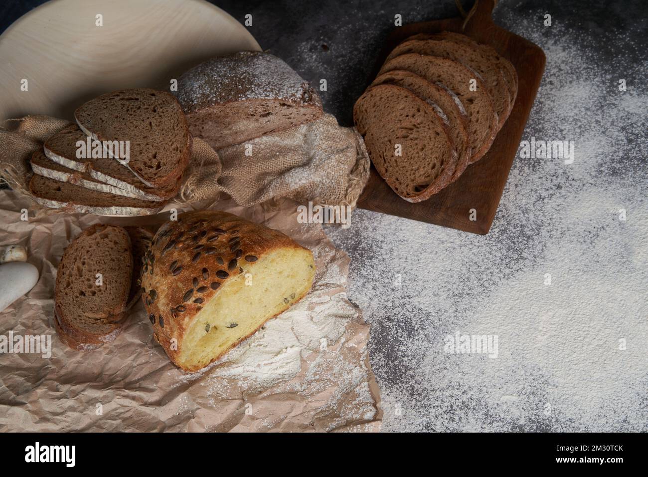 Different types of sliced bread and a loaf on a wooden background ...