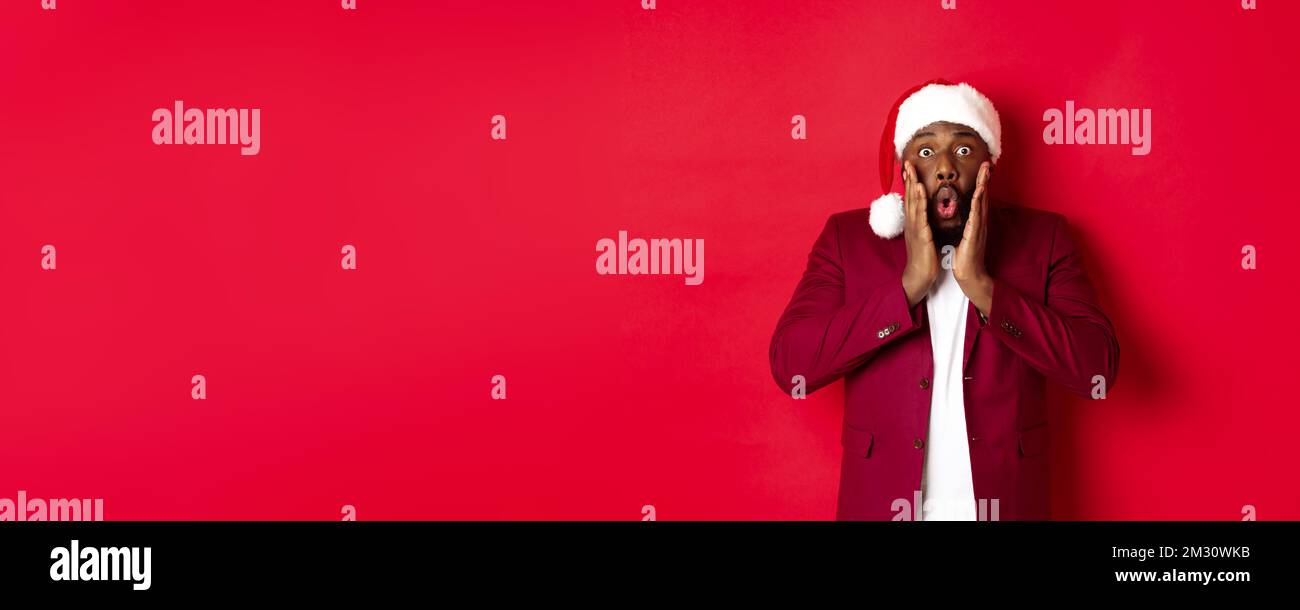 Christmas, party and holidays concept. Shocked Black man in santa hat ...