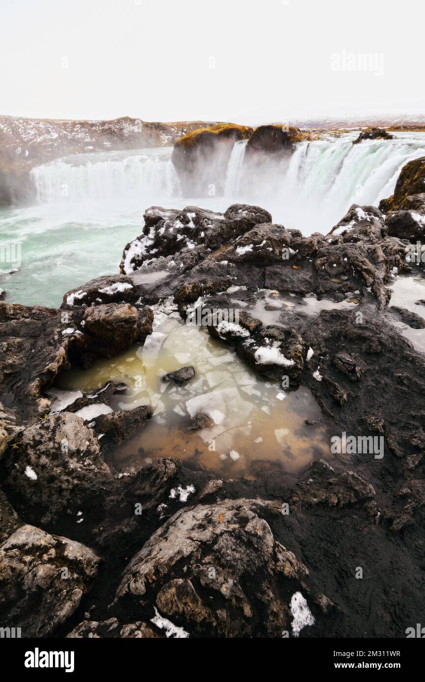 A vertical shot of a beautiful waterfall near the rocks in Iceland ...