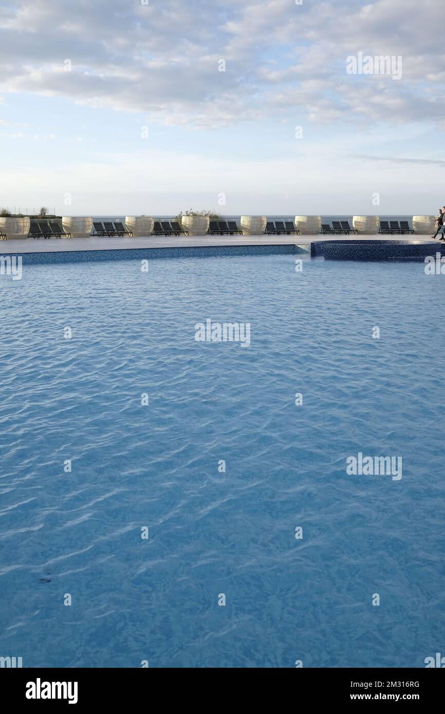 The vertical view of a swimming pool with empty folding chairs around ...