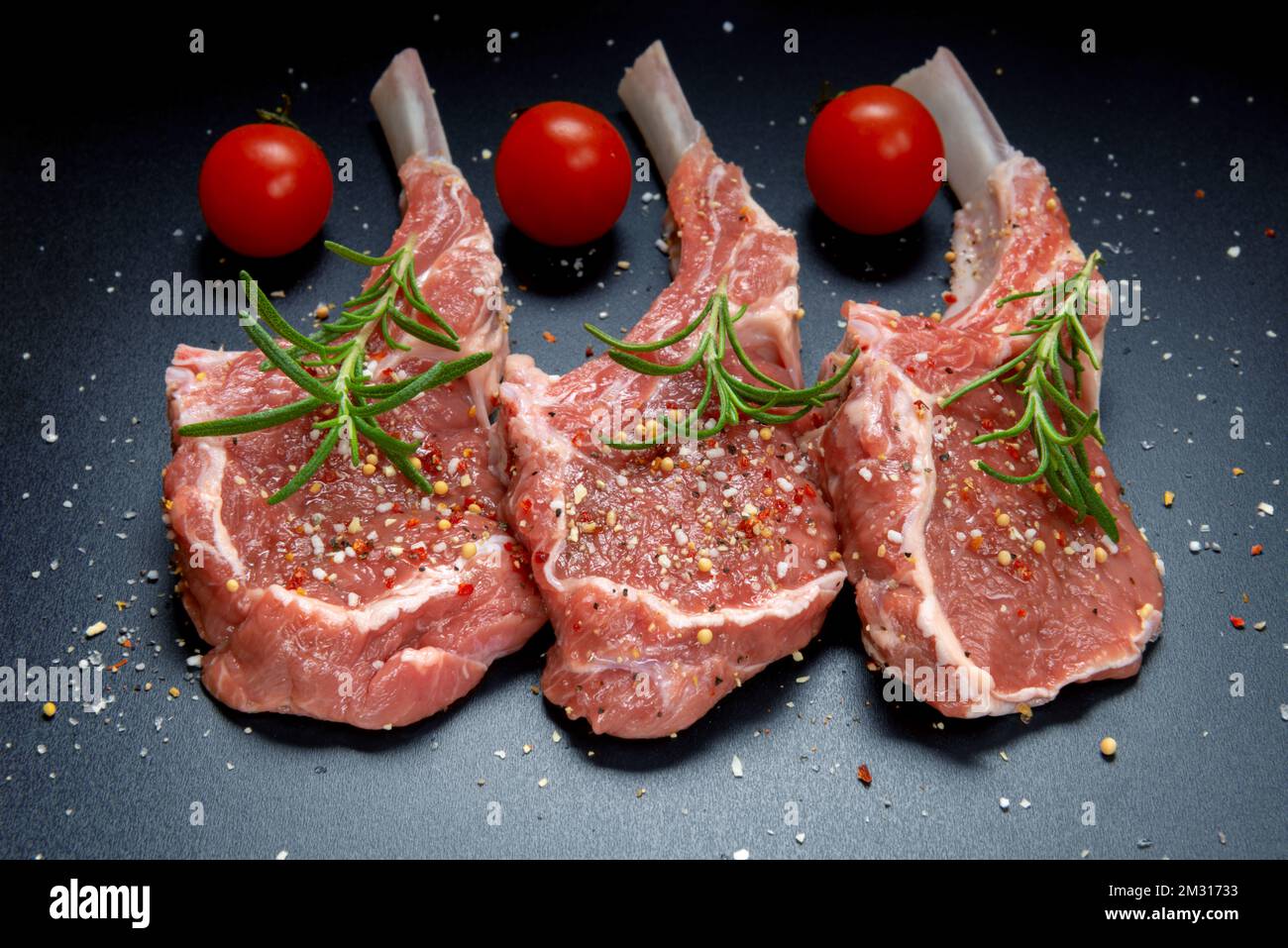 raw lamb saddle meat on bone with salt, pepper decorated rosemary and ...