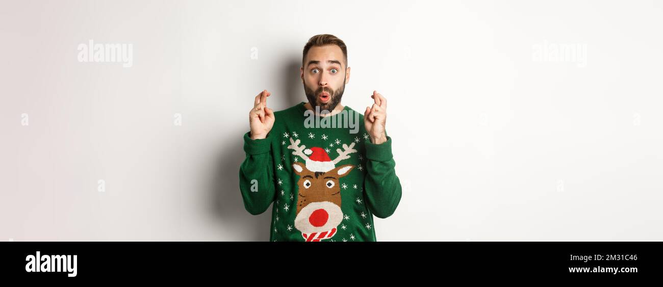 Christmas, holidays and celebration. Excited guy making wish, keep ...