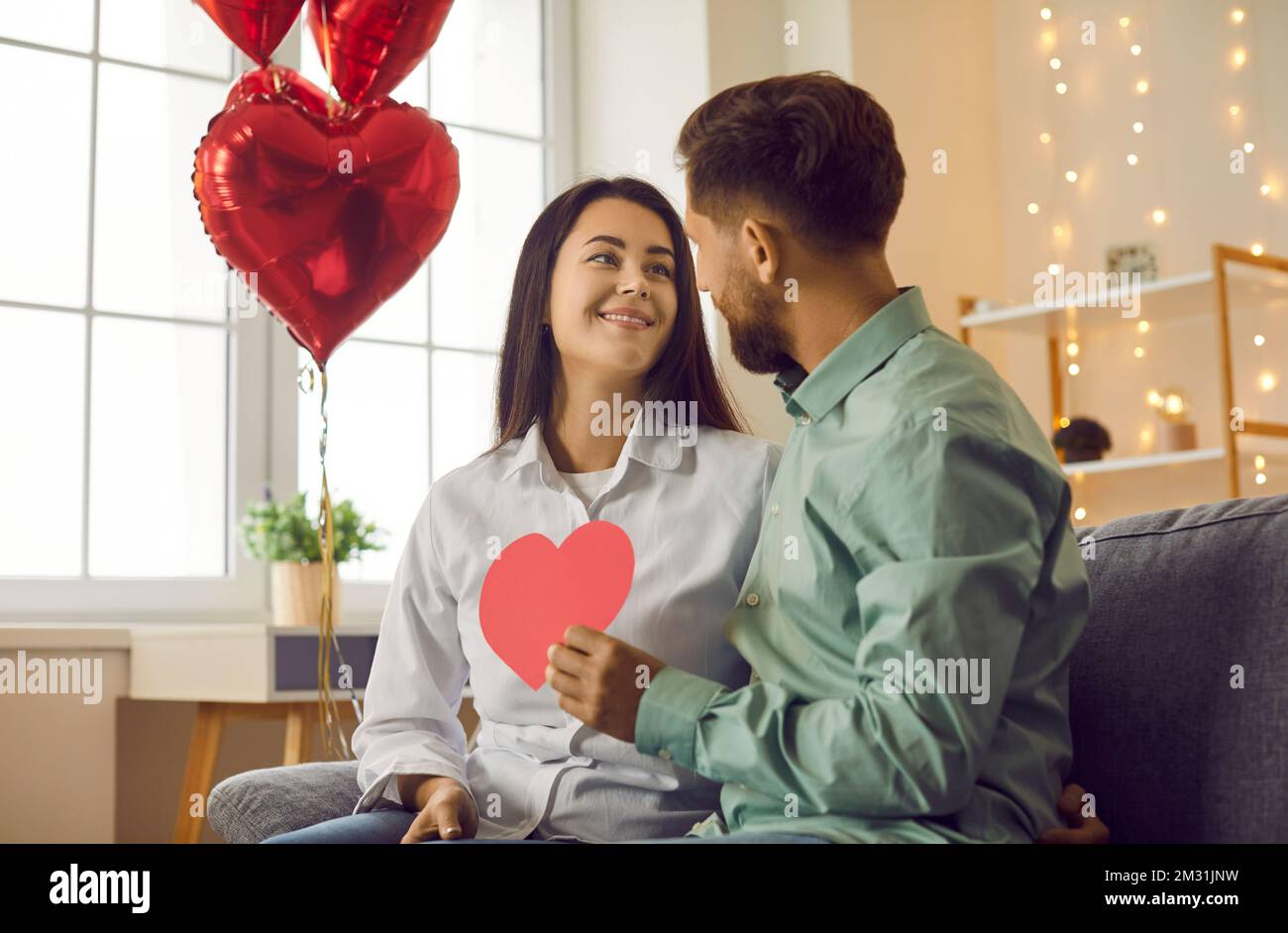 Young couple in love in romantic atmosphere are sitting on the sofa in ...