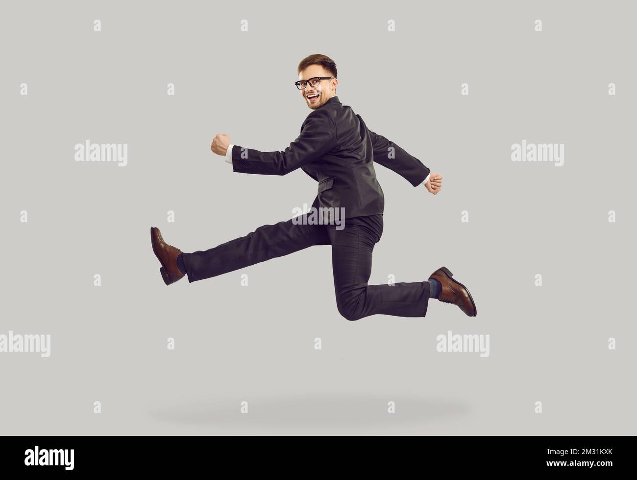 Young Caucasian man jumping and smiling posing in pose of runner ...
