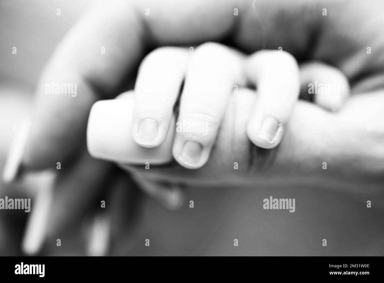 Close-up of a baby's small hand with tiny fingers and arm of mother ...