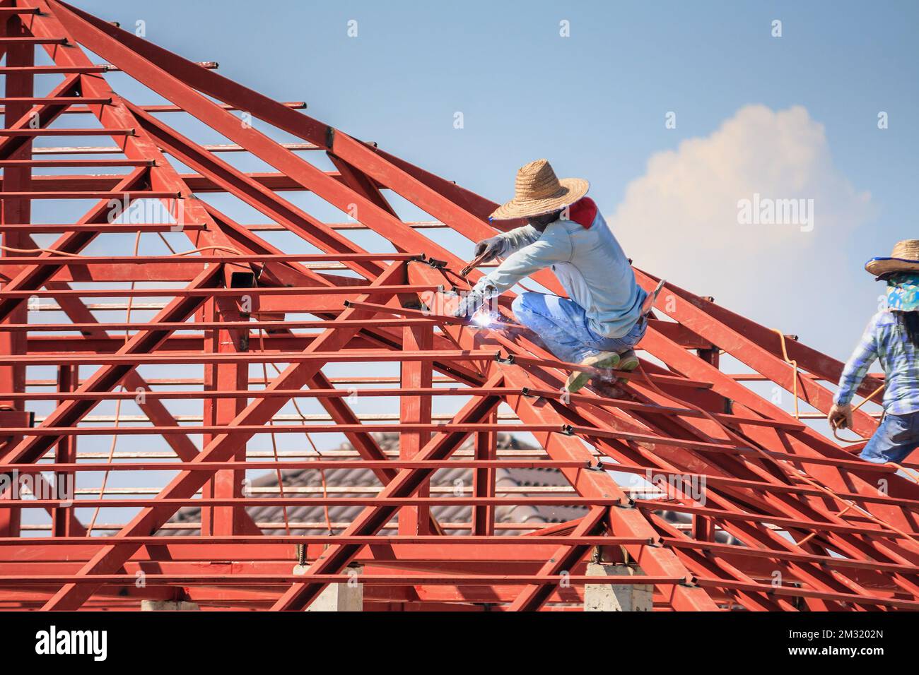 Construction welder workers installing steel frame structure of the house roof at building ...