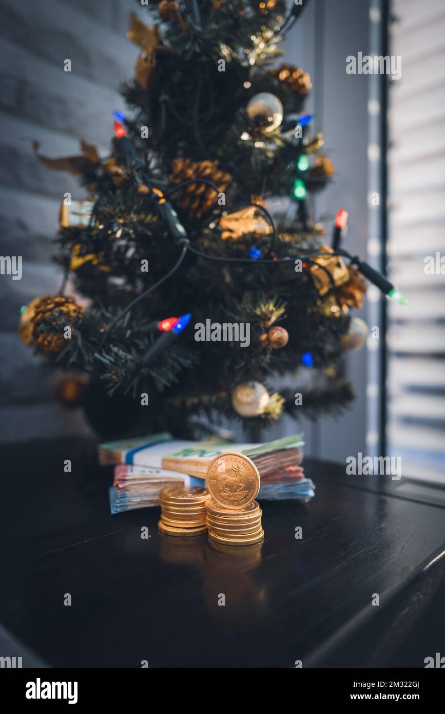 under a christmas tree lies a bundle of cash and a stack of Krugerrand ...