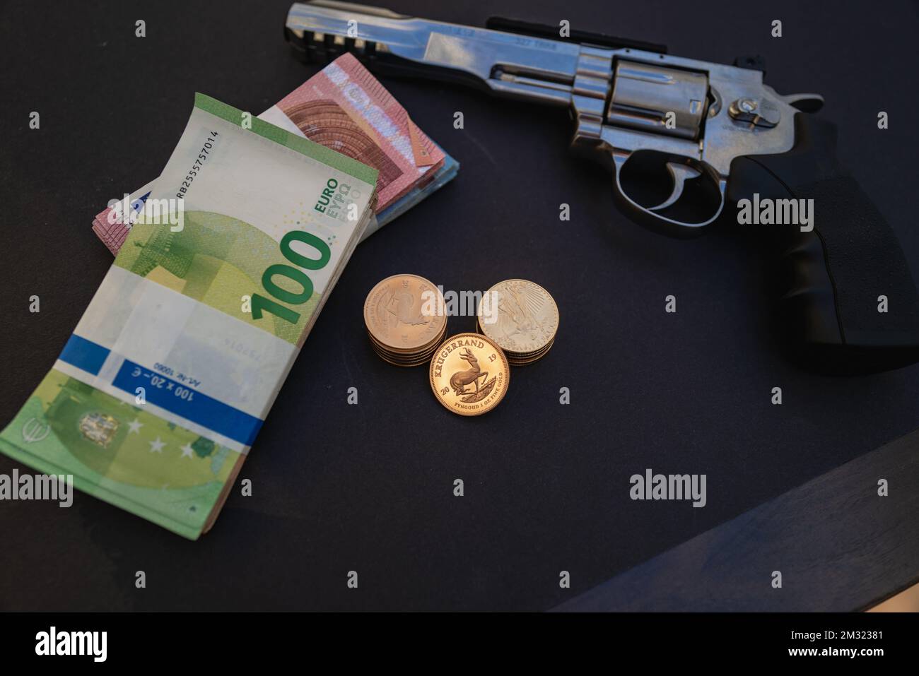 next to a wad of cash and a stack of Krugerrand gold coins lies a ...