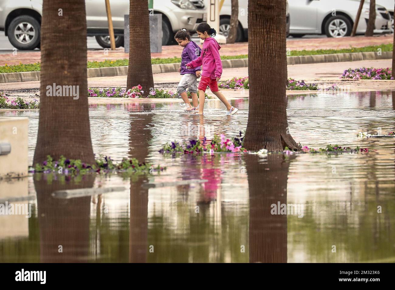 Two girls wade through water on the sidewalk, in the flooded streets ...