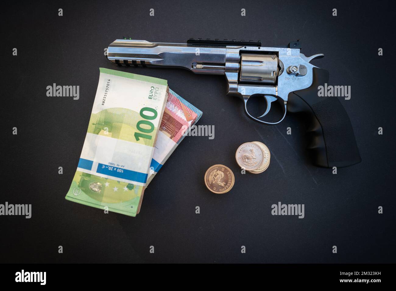 next to a wad of cash and a stack of Krugerrand gold coins lies a ...