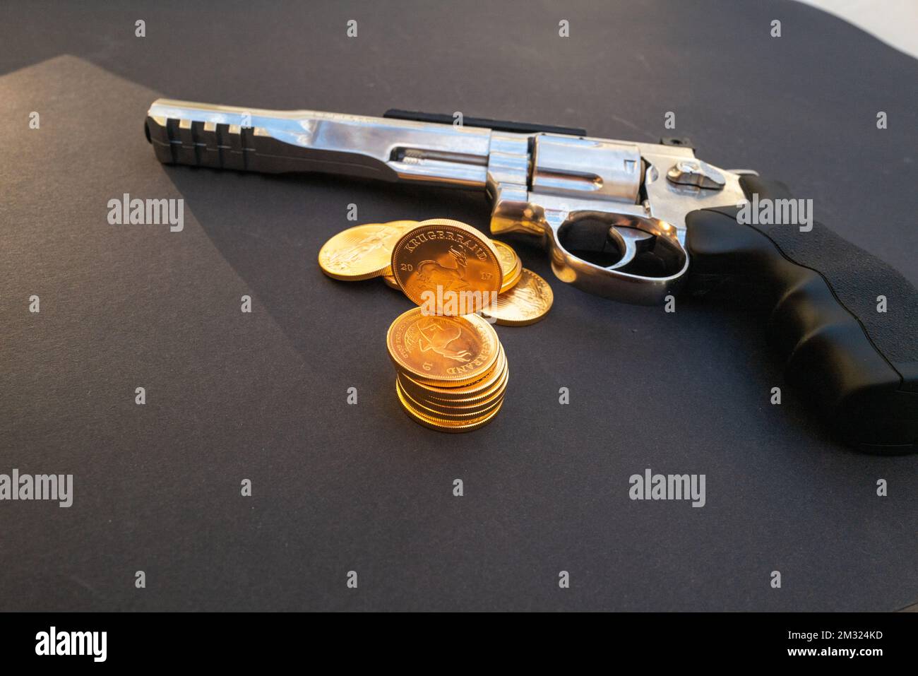 next to a stack of Krugerrand gold coins lies a revolver Stock Photo ...