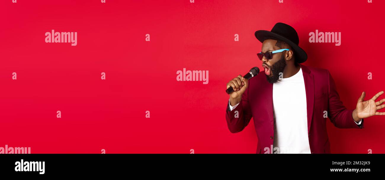 Passionate black male singer performing against red background, singing ...