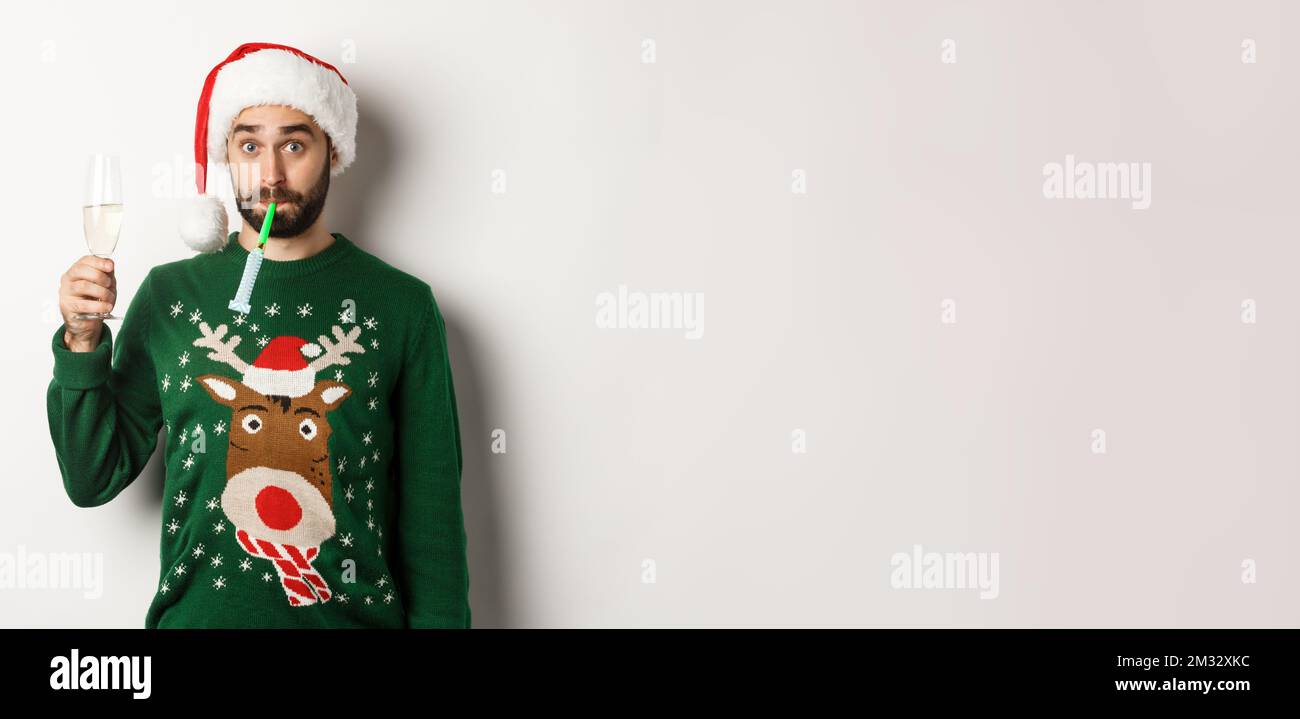 Christmas and holidays concept. Funny guy in Santa hat blowing a party ...