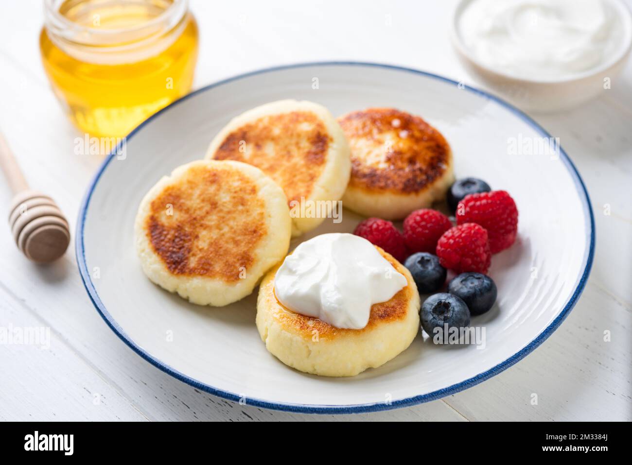 Cottage cheese fritters Syrniki with sour cream, honey and berries ...