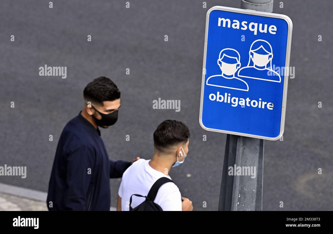 Illustration picture shows two men wearing a mask as they pass a sign ...