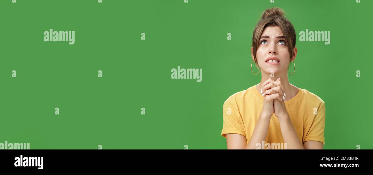 Intense nervous and faithful good-looking young woman clenching hands ...