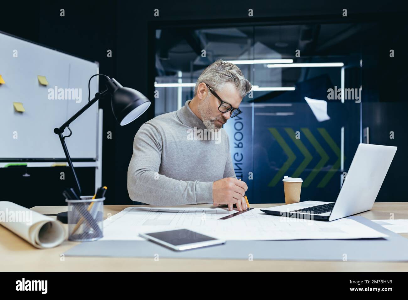 Handsome gray-haired senior man architect, designer, engineer makes a ...