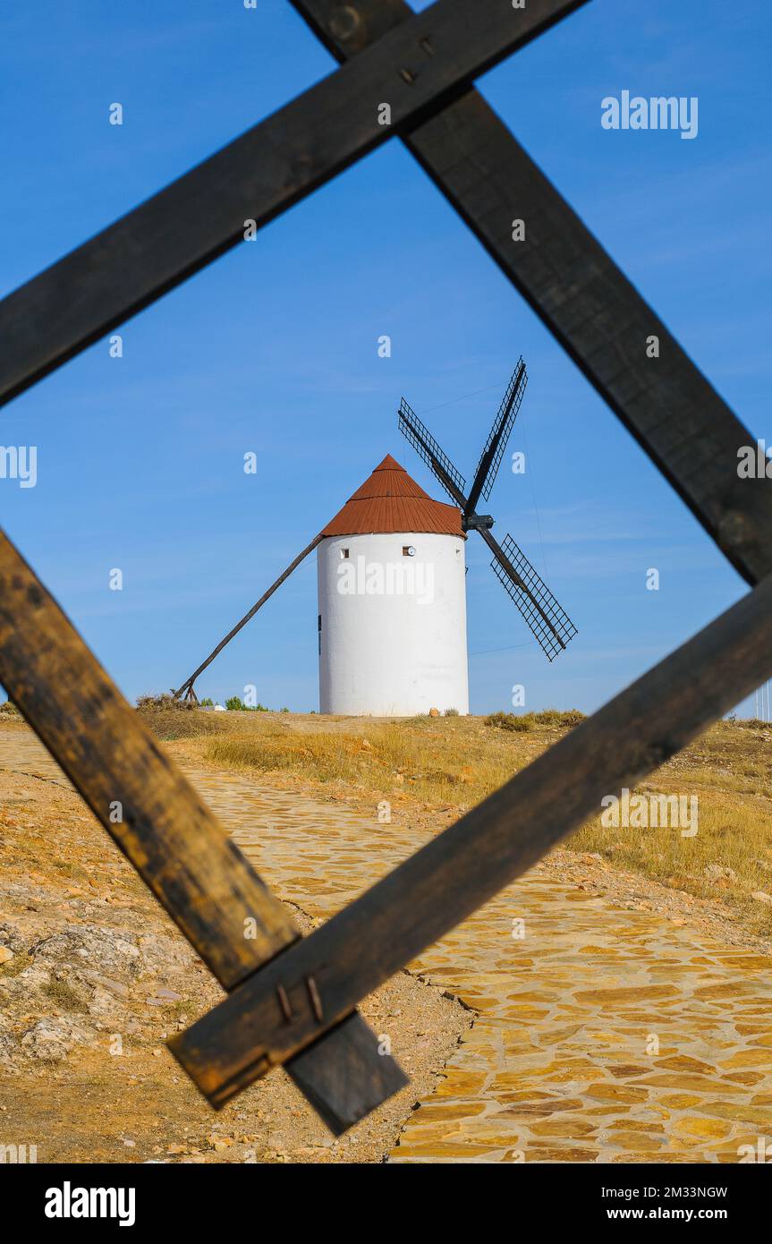 A vertical shot of a white windmill with a red roof under the blue sky ...
