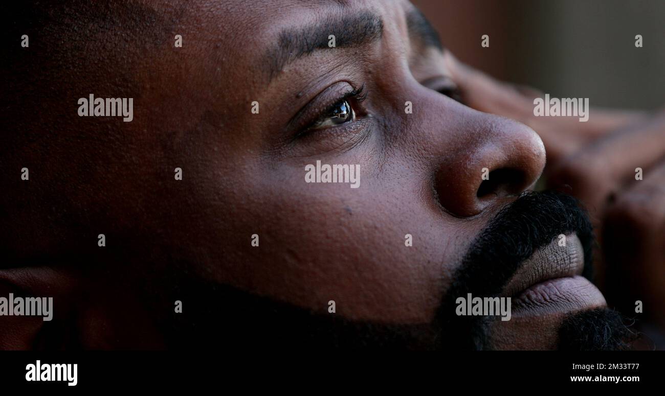 Pensive worried black African man close-up eyes looking up to sky ...