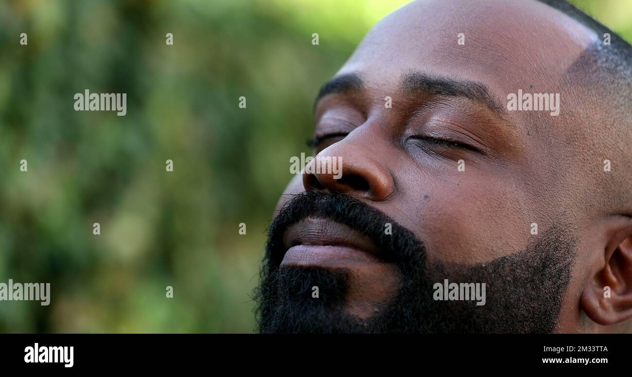 Positive African breathing fresh air outside, happy close-up face ...