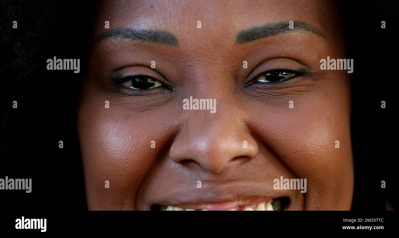 Positive African woman opening eyes smiling at camera, macro close-up ...