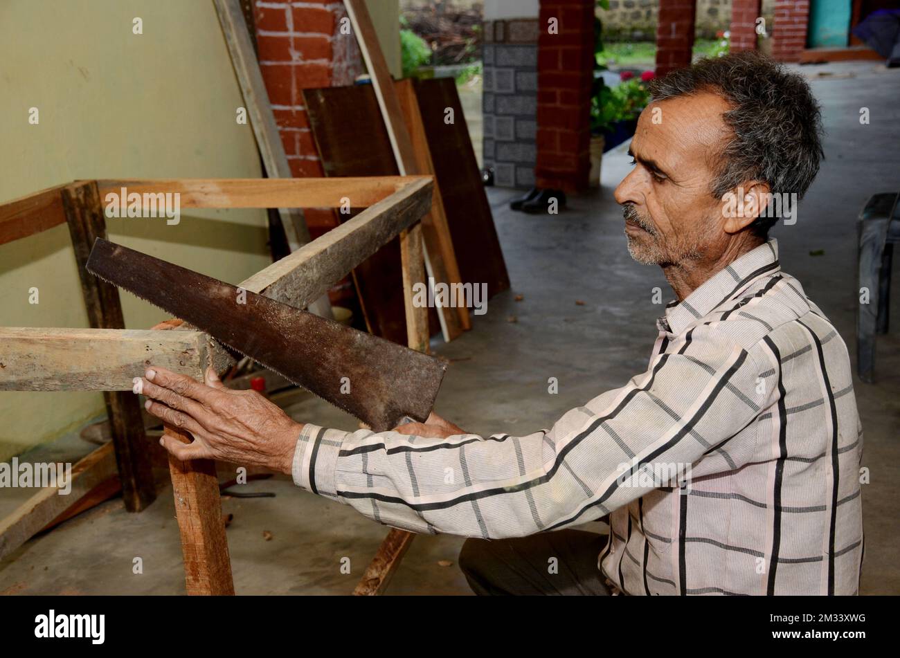 An Indian old man working in a wood workshop with a saw Stock Photo - Alamy