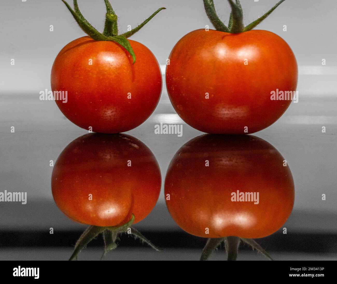 Two red tomatoes with reflection from a dark reflective surface Stock ...