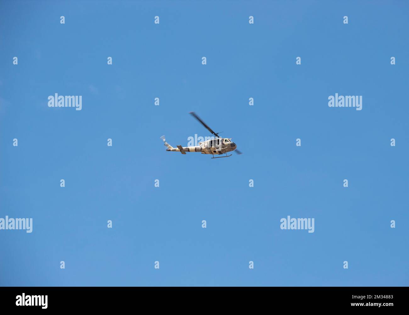 Yellow and green army helicopter flying with blue sky at background ...