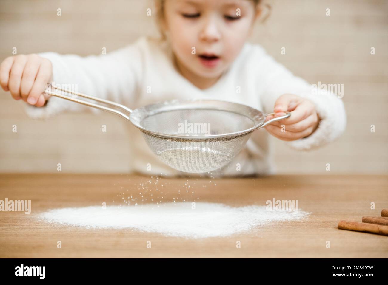 close up little girl is cooking in the kitchen.cute kid sifts flour ...