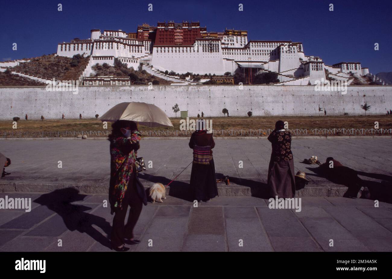 Women in traditional dresses with their pet dog and an umbrella in ...
