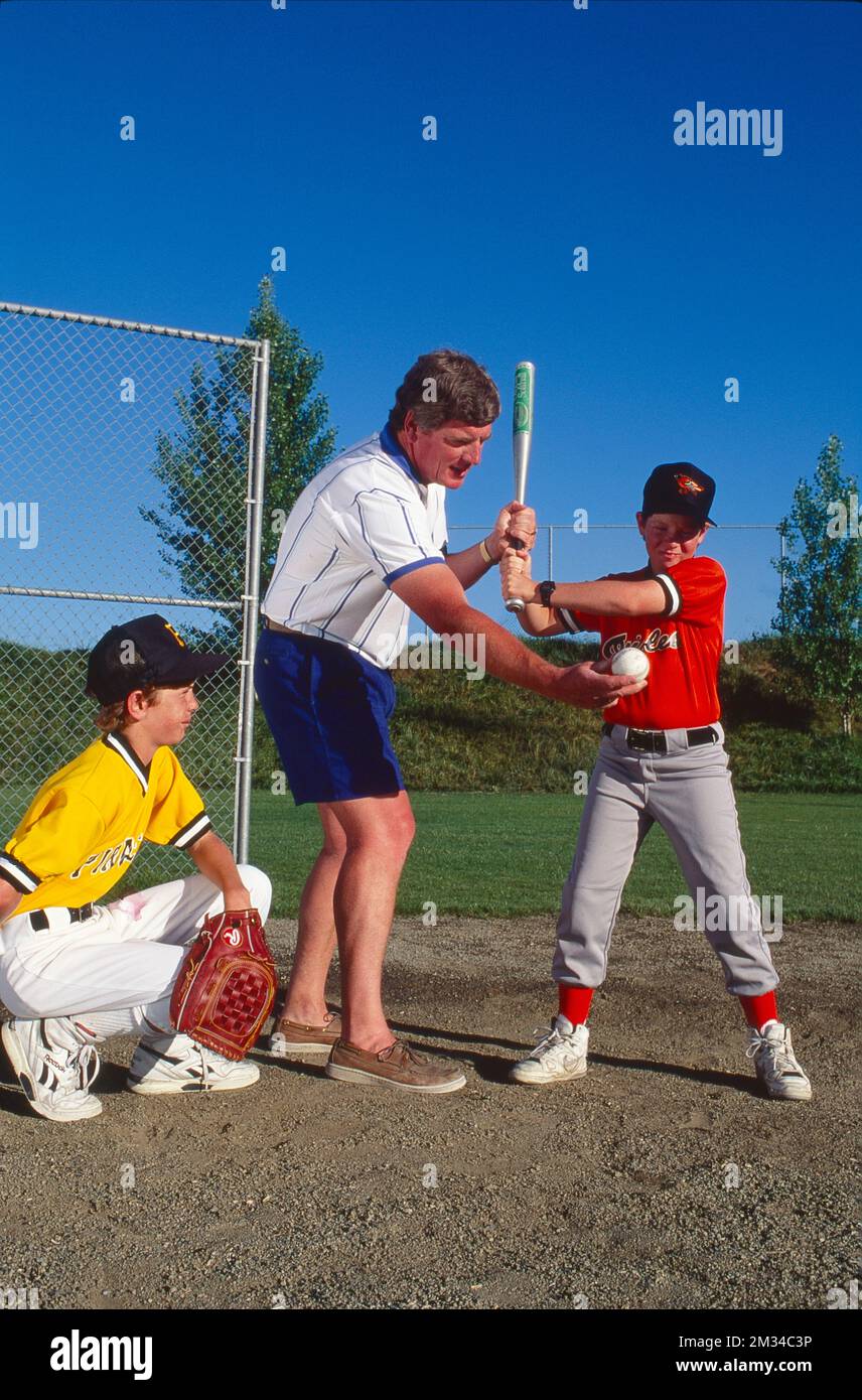 Father working with two boys on how to hit a baseball Stock Photo - Alamy