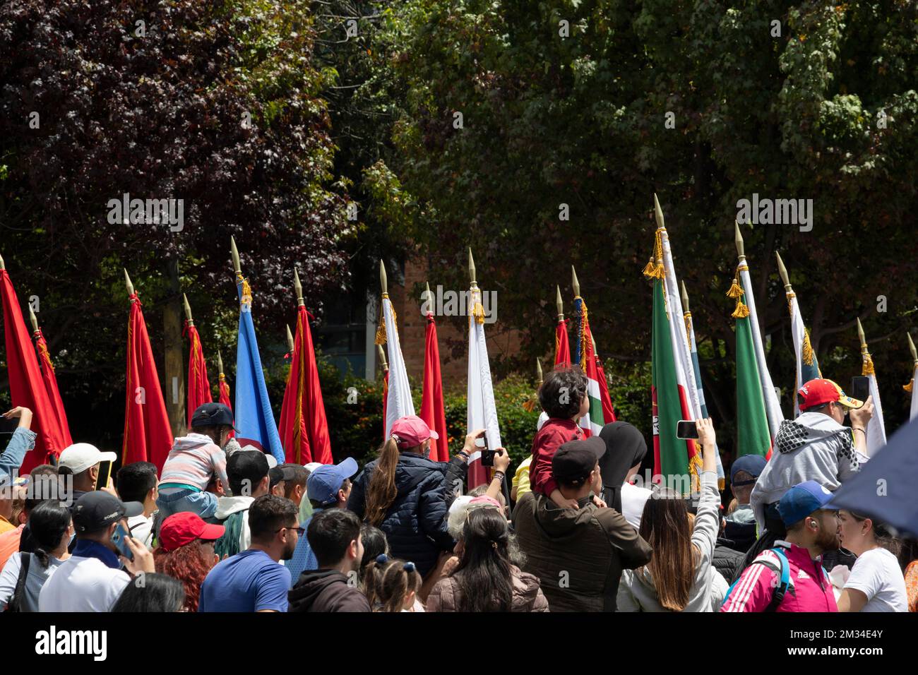 crowd with kids over shoulders watching colombian armed forces flags ...