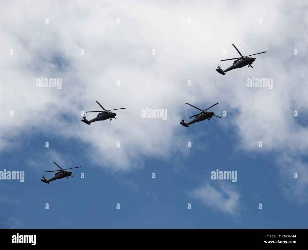 Four Black Hawk helicopters flying over crowd with blue and cloudy sky during colombian ...