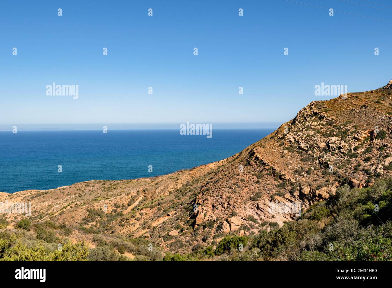 A sea and blue sky landscape with a cliff in the foreground Stock Photo ...