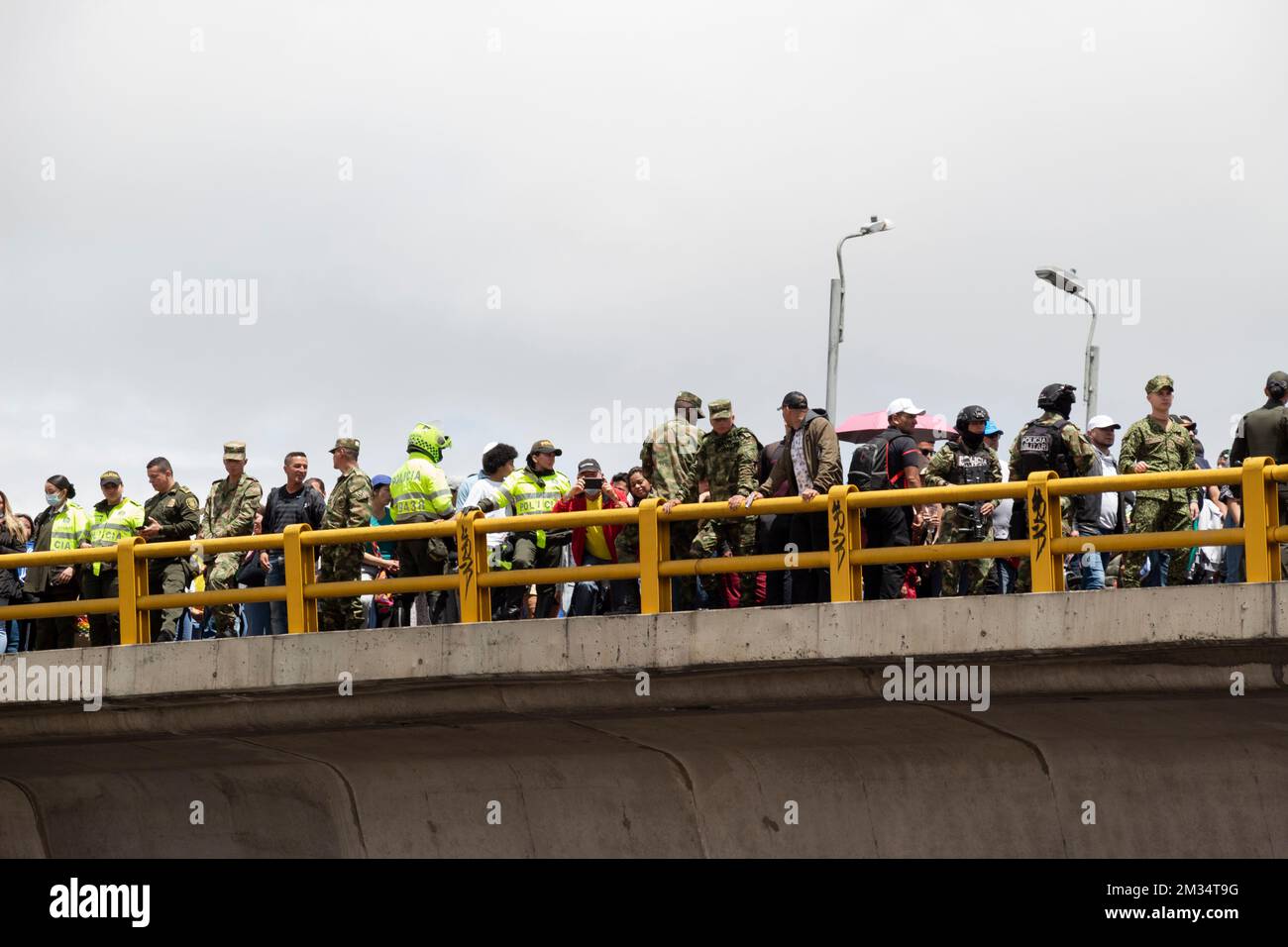 Military and police troops over a bridge with crowd trying to watch ...